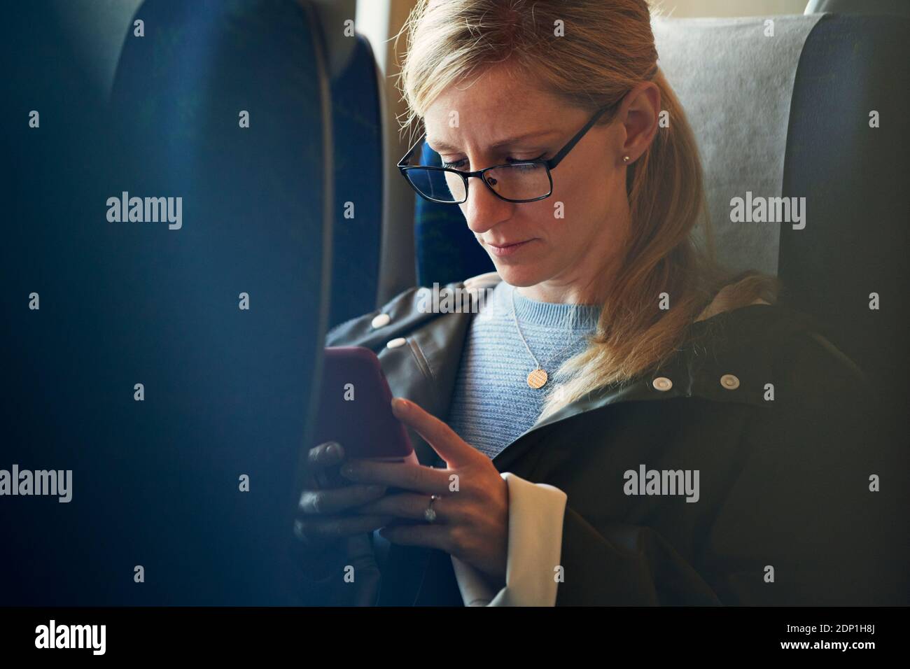 Woman in train using cell phone Stock Photo - Alamy
