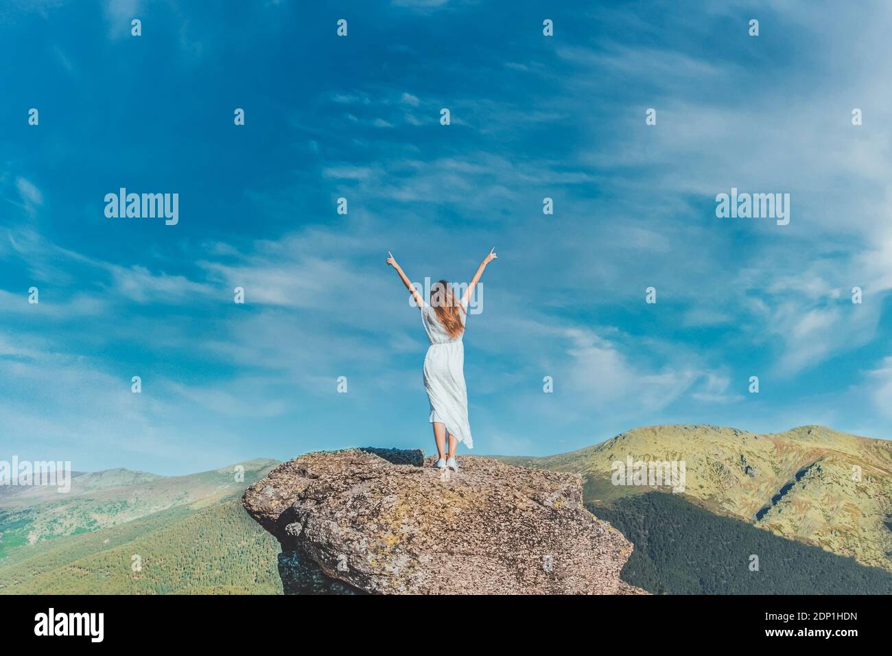 Woman from behind with white dress and her arms raised on top of a ...
