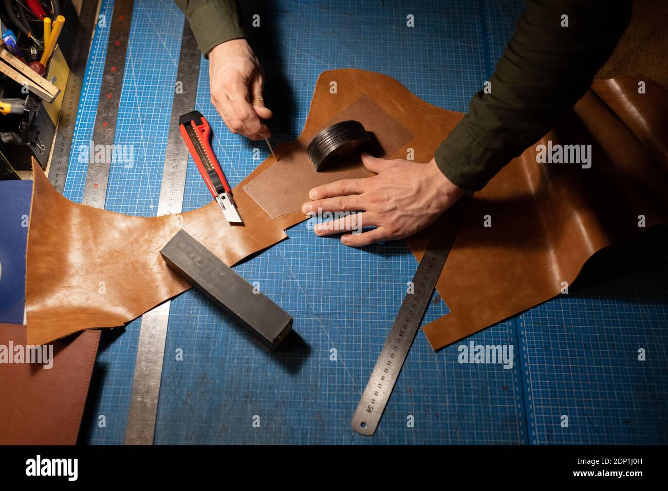 From above unrecognizable craftsman piercing piece of leather with ...