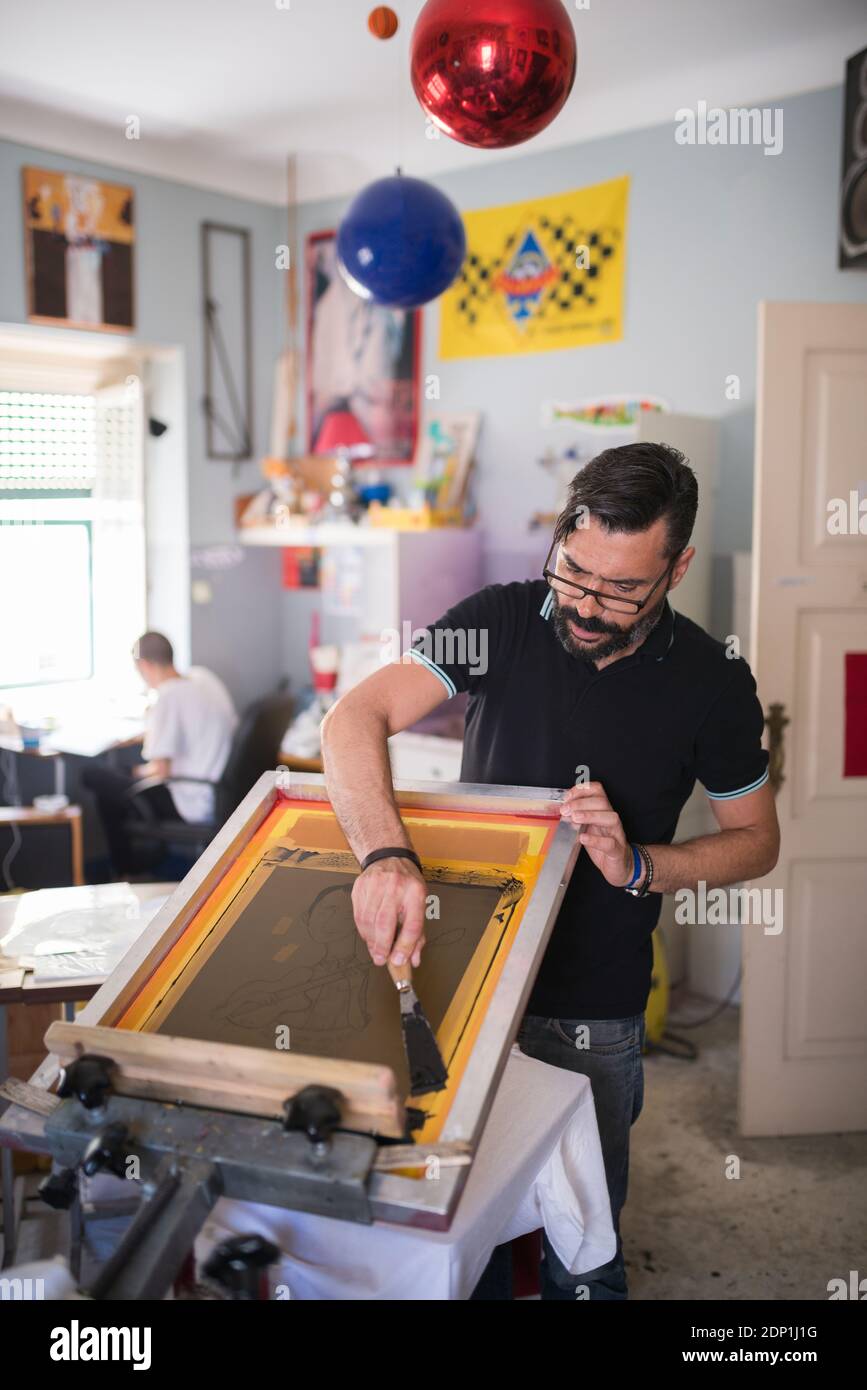 Man operating screen printing equipment Stock Photo - Alamy