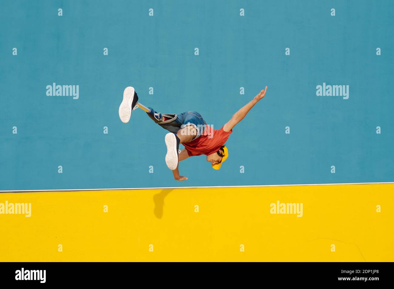 Athlete practicing handstand while jumping against multi colored wall ...