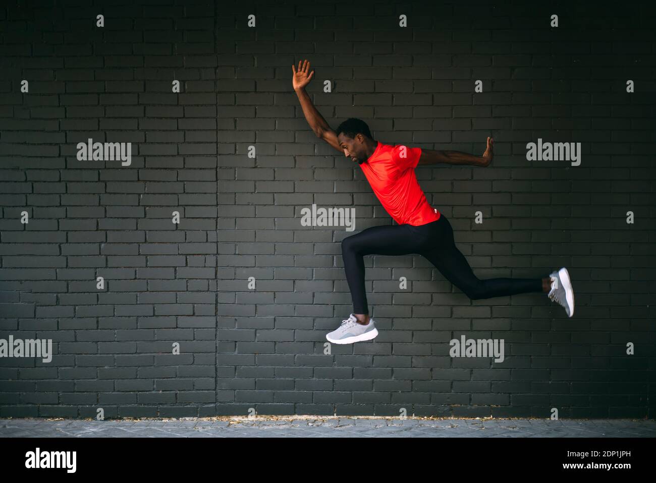 Young sportive man jumping in front of a brick wall Stock Photo - Alamy