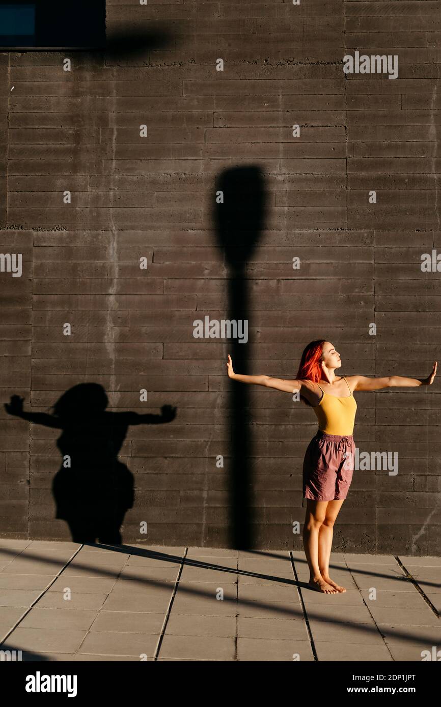 Woman dancing barefoot with black urban wall background and her shadow ...