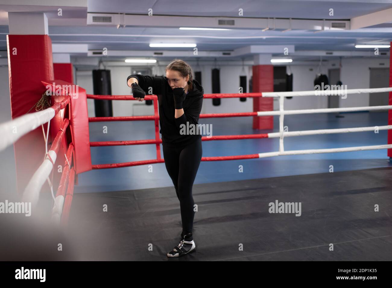 Full length powerful woman in sportswear doing hook punch while ...