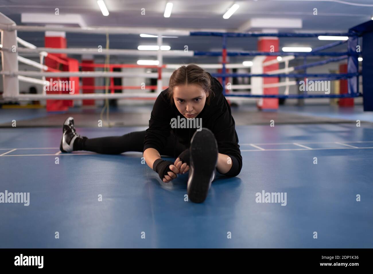 Strong woman in sportswear bending to leg and doing stretching exercise ...