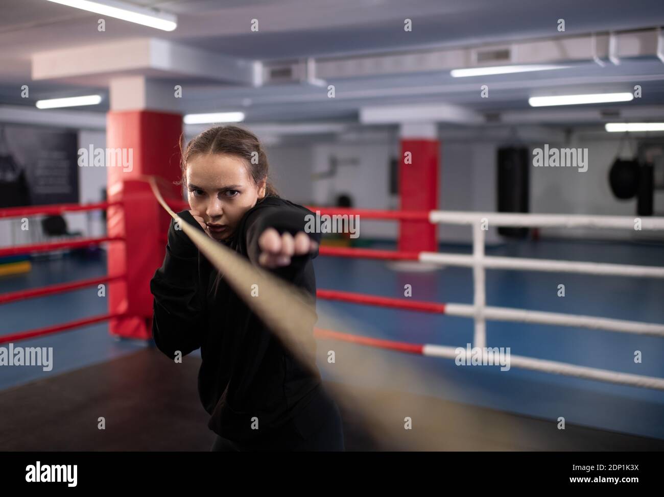 Concentrated sportswoman doing jab punch towards camera while ...