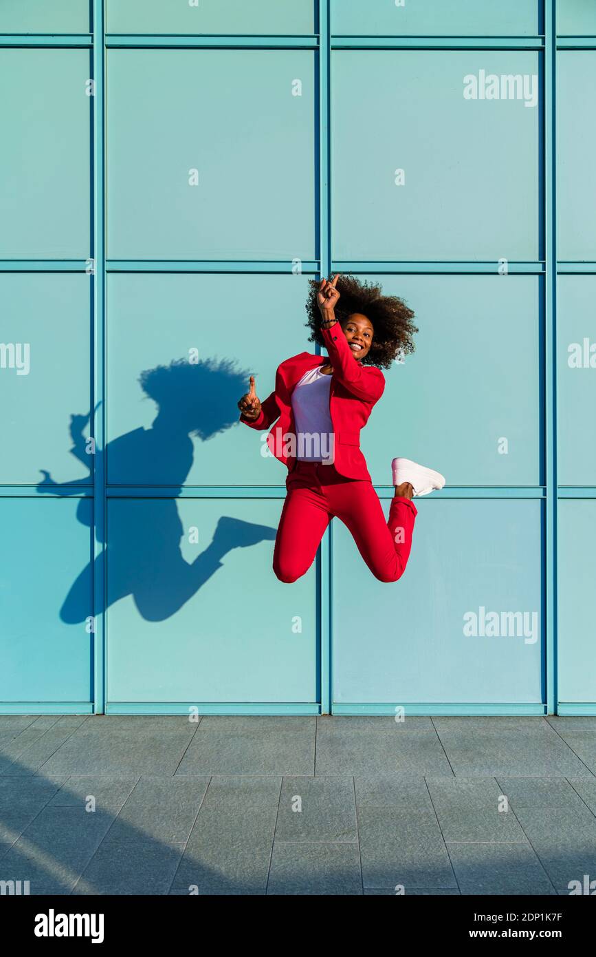 Woman enjoying while jumping against wall Stock Photo - Alamy