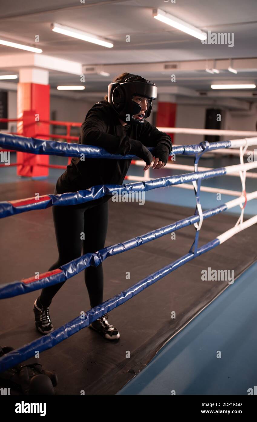 Full body tired sportswoman in protective helmet and sportswear leaning ...