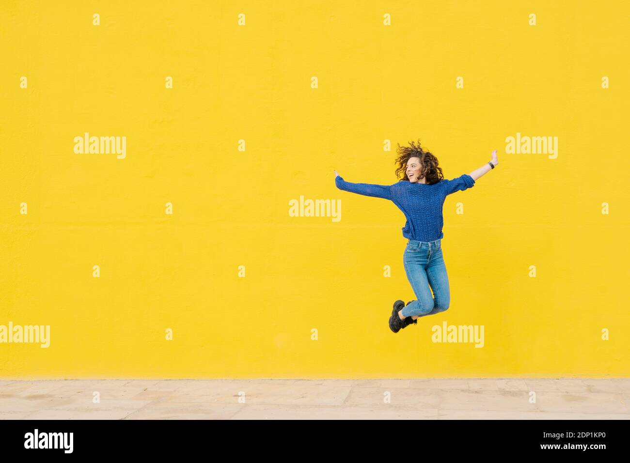 Young woman jumping in the air in front of yellow background Stock ...
