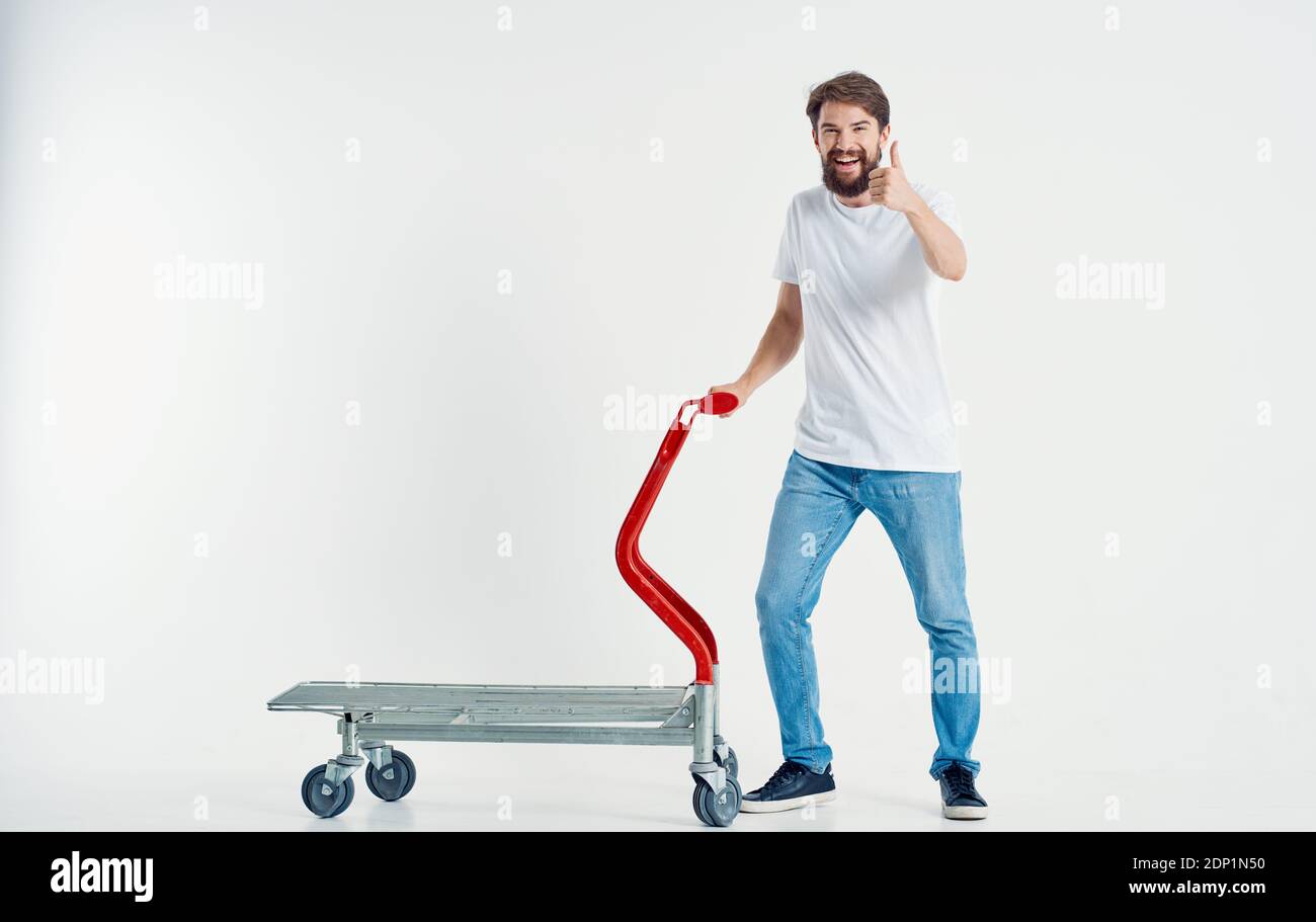 cargo trolley man in jeans and sneakers light background work ...