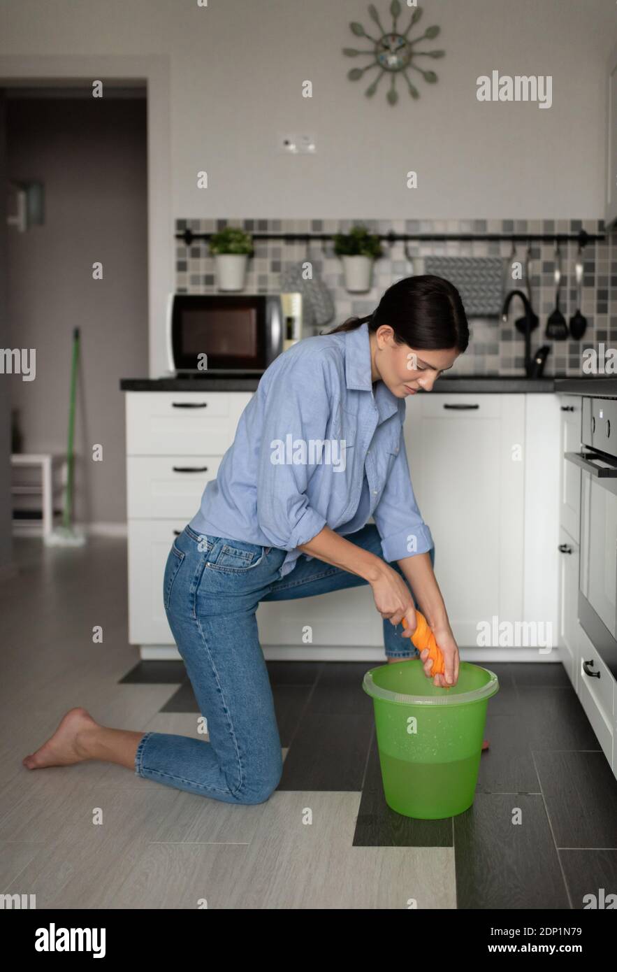 Side view of young female in casual shirt and jeans kneeling and ...