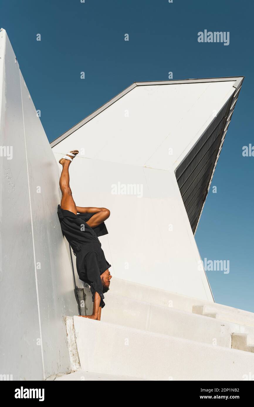 Young man wearing black kaftan doing a handstand outdoors Stock Photo ...