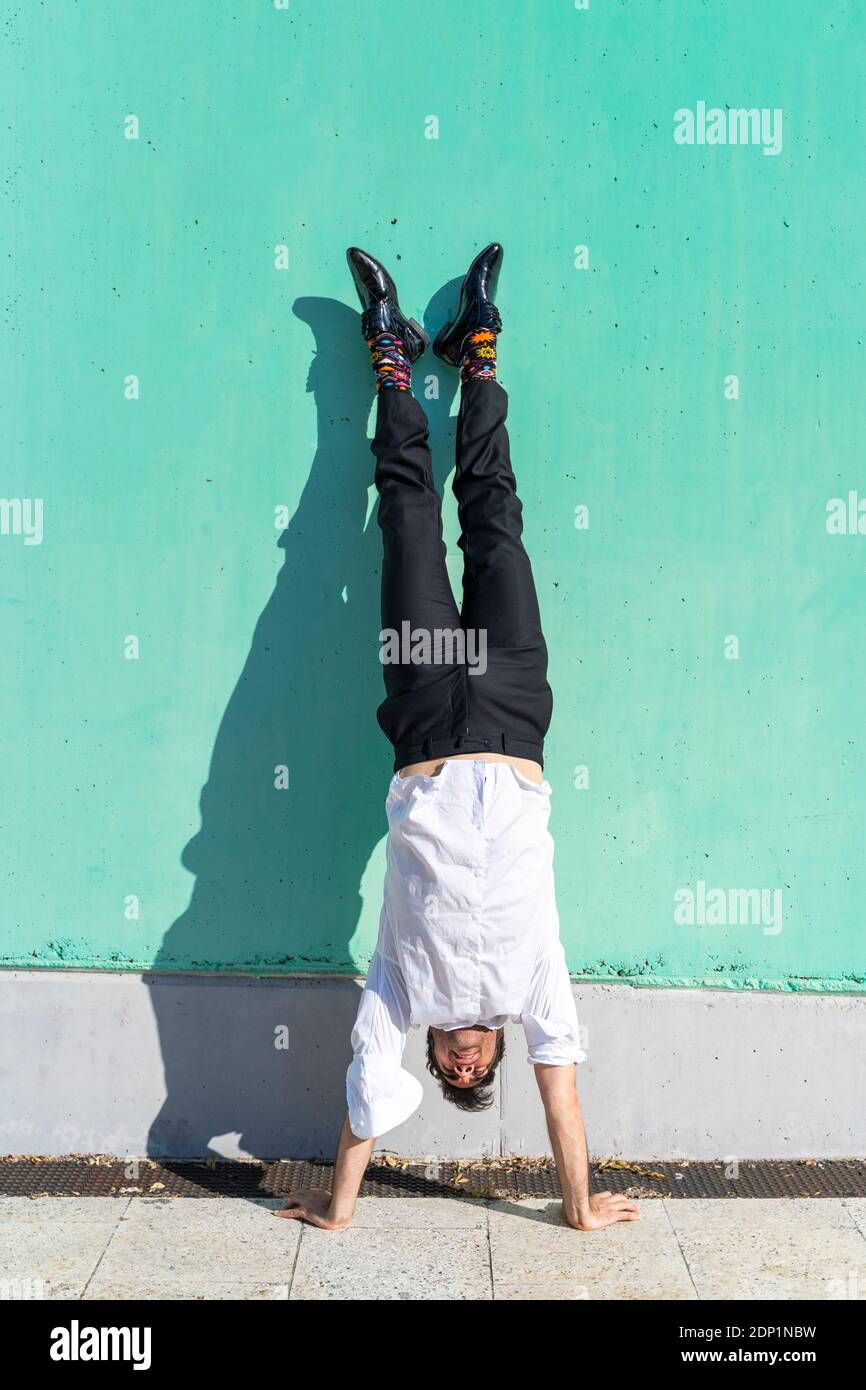 Businessman doing handstand against green wall Stock Photo - Alamy