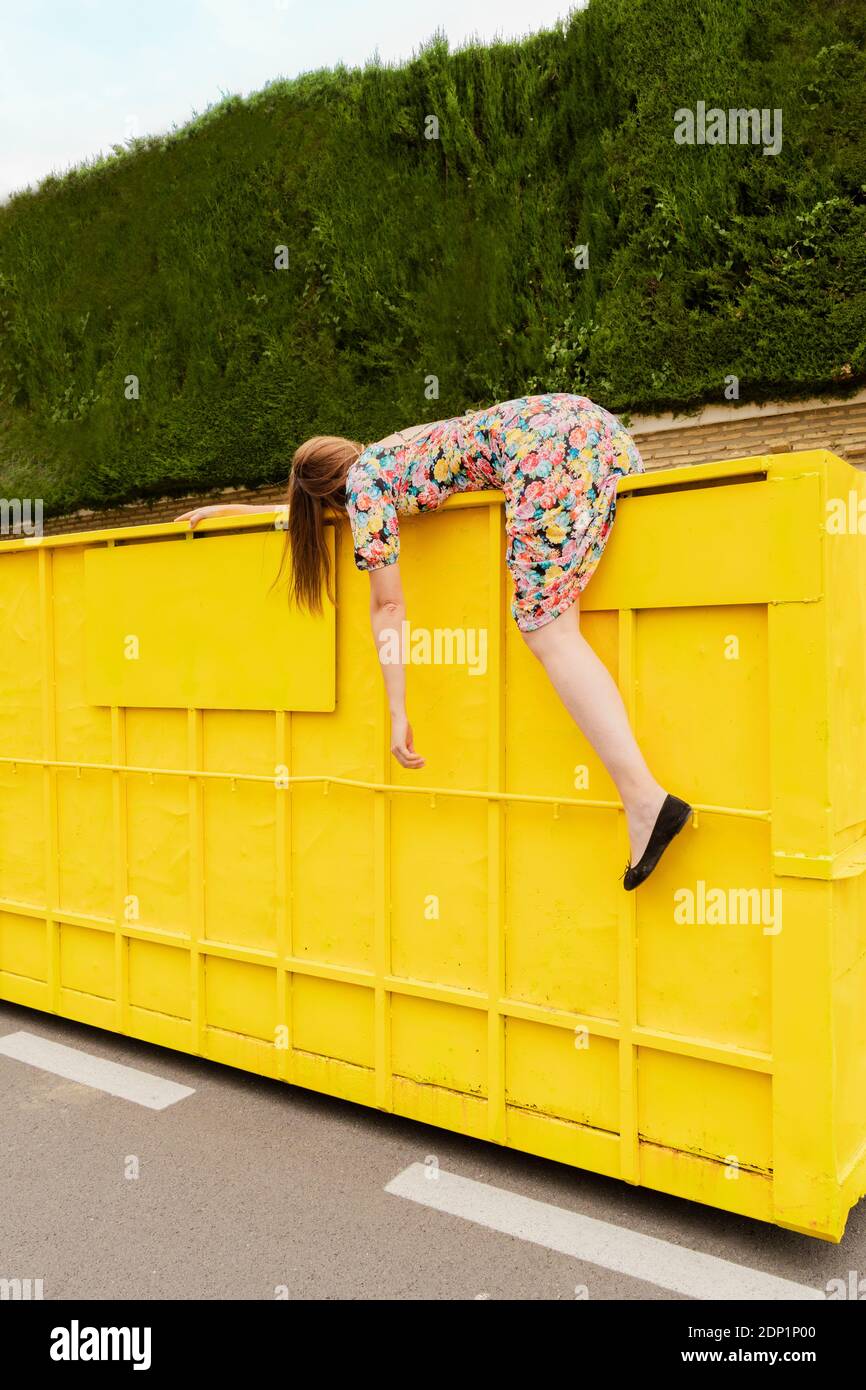 Exhausted woman hanging over edge of yellow container Stock Photo - Alamy