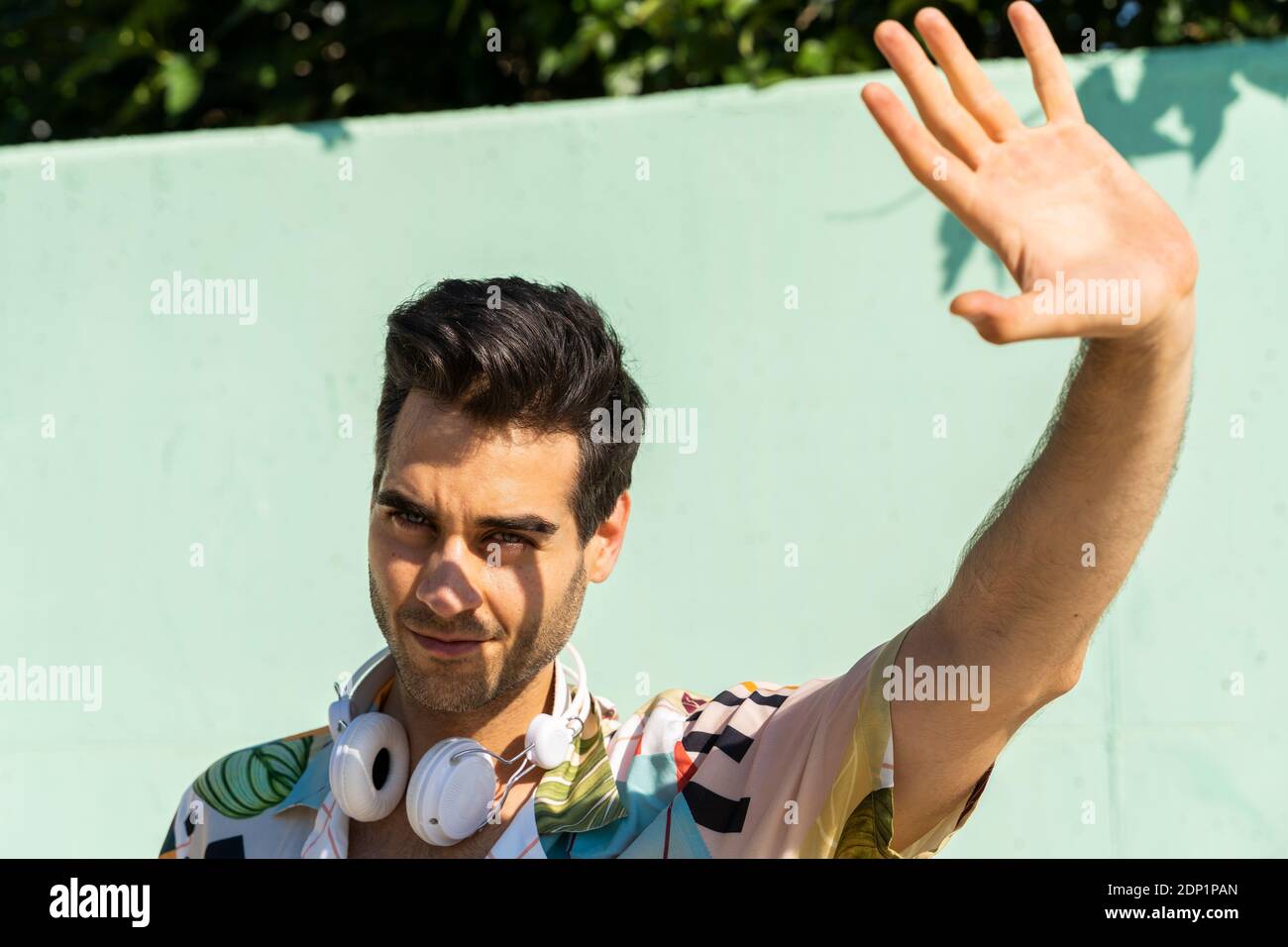 Casual man in front of colorful wall shielding face with his hands ...