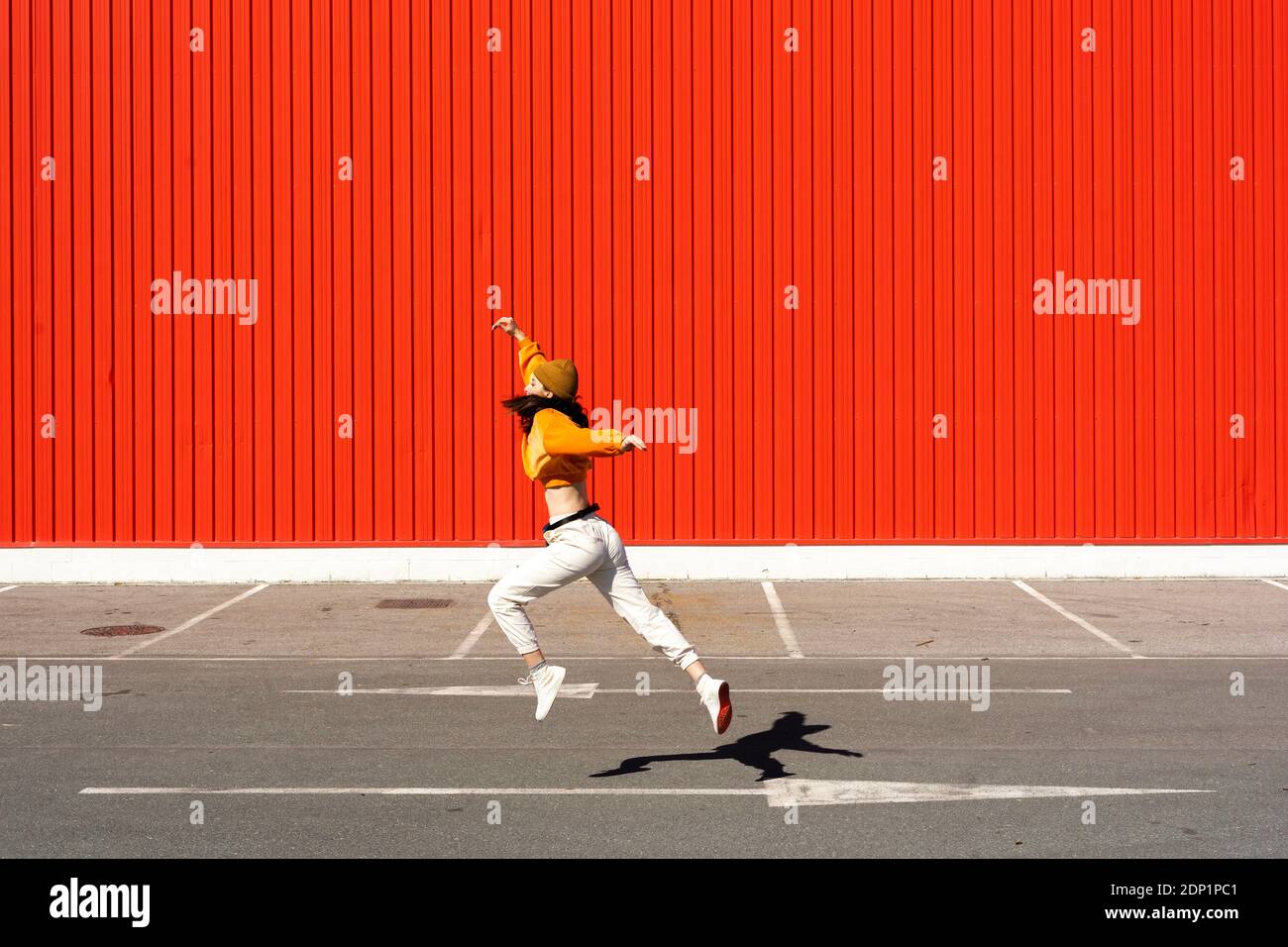 Young woman dancing in front of a red wall Stock Photo - Alamy