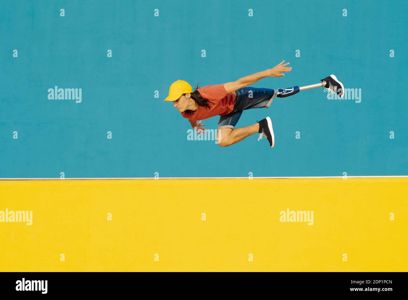 Athlete with artificial limb and foot jumping against multi colored ...
