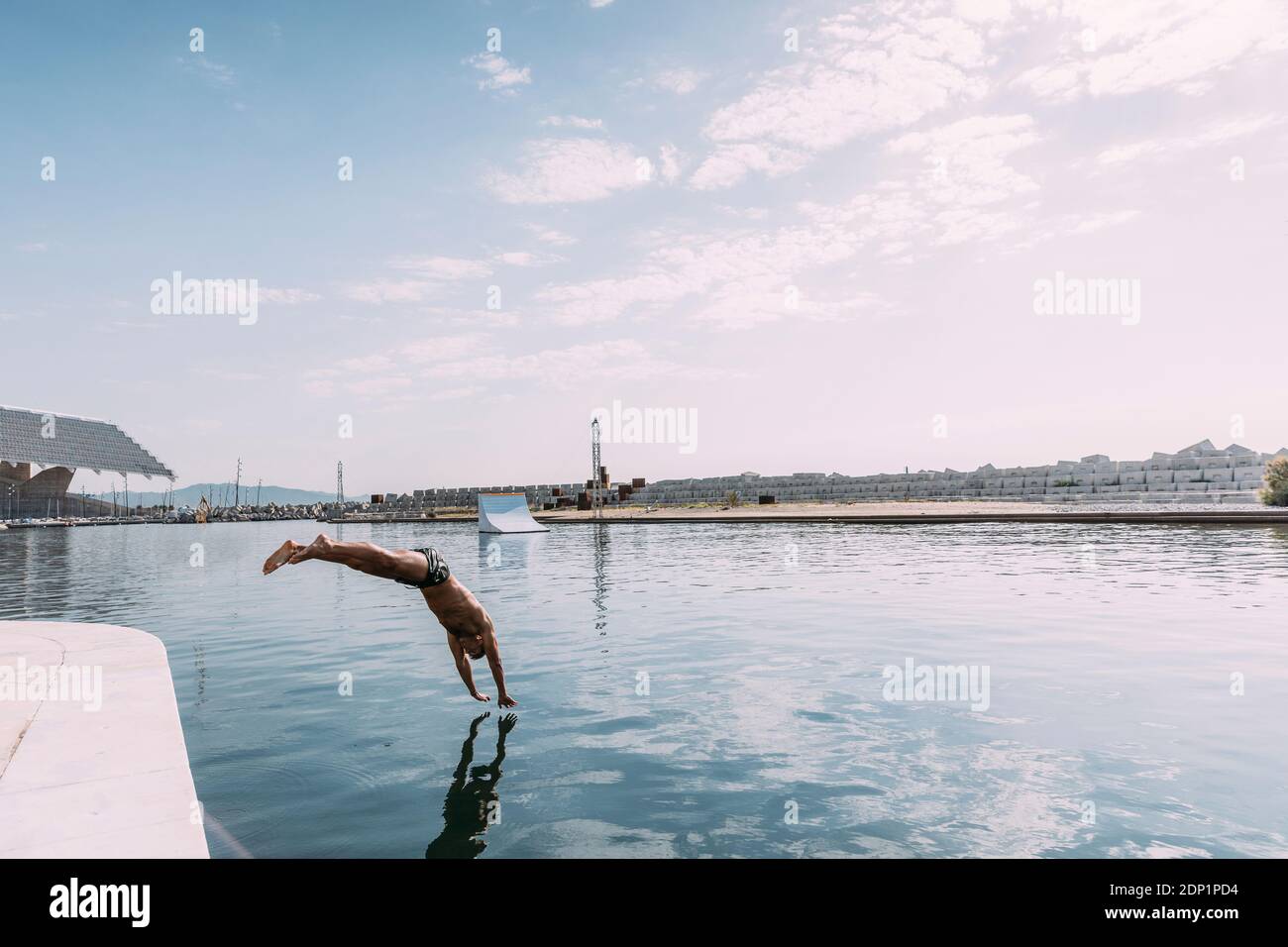 Young man jumping into water from a pier Stock Photo - Alamy