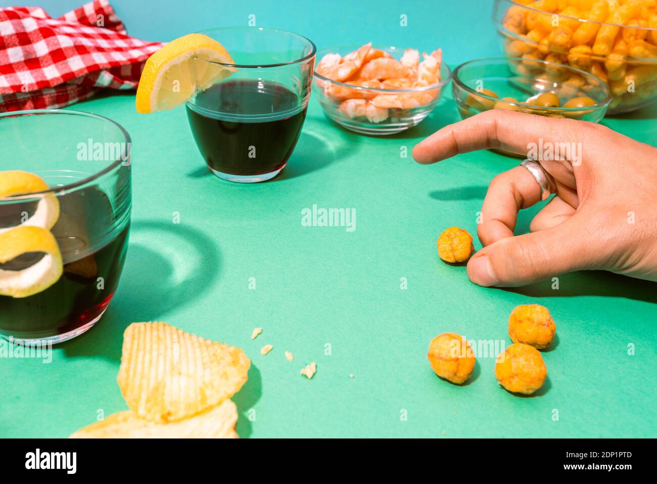 Hand of man playing with cheese puffs on table set with various snacks ...