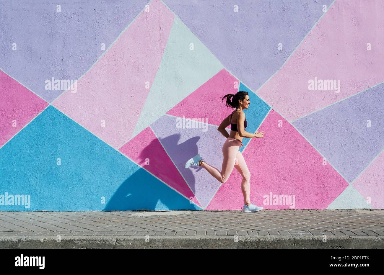 Mature woman running in front of a colorful wall Stock Photo - Alamy