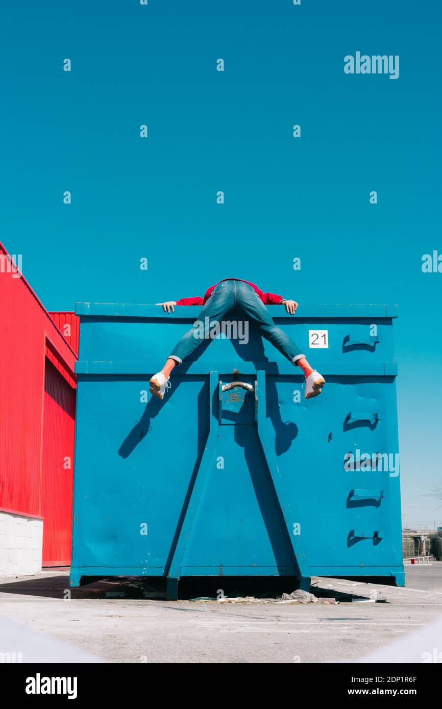 Young man hanging over edge of blue container, rear view Stock Photo ...