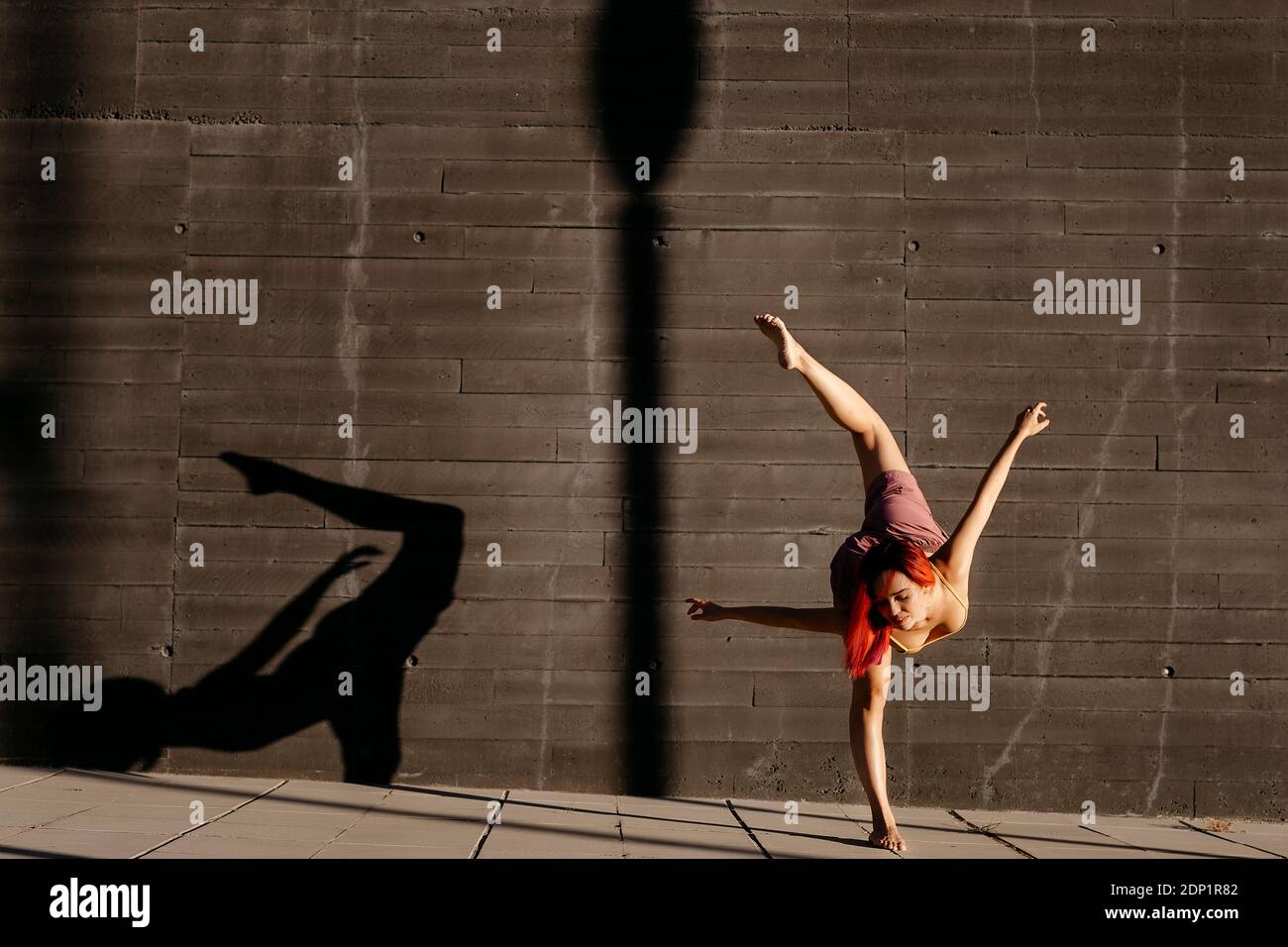Woman dancing barefoot with black urban wall background and her shadow ...