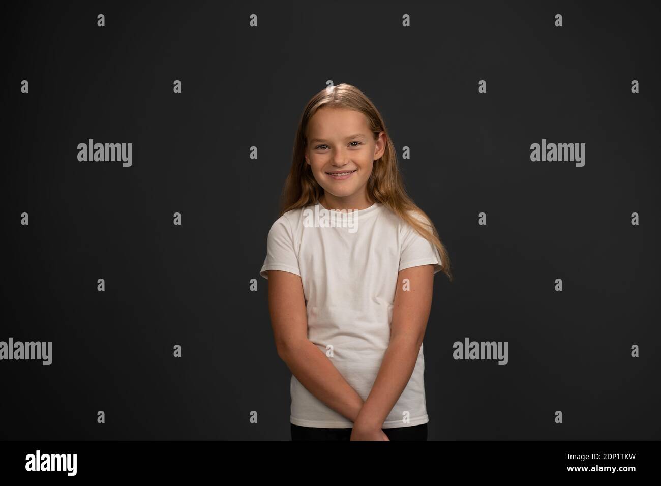 Smiling girl looking timid or frustrated at the camera wearing white t ...