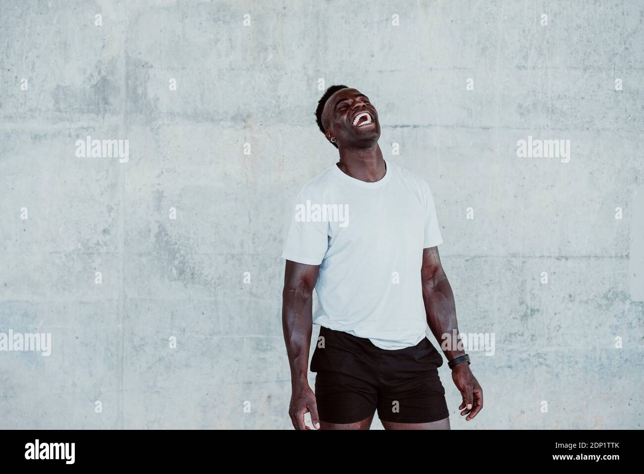 Sportsman laughing while standing against wall Stock Photo - Alamy