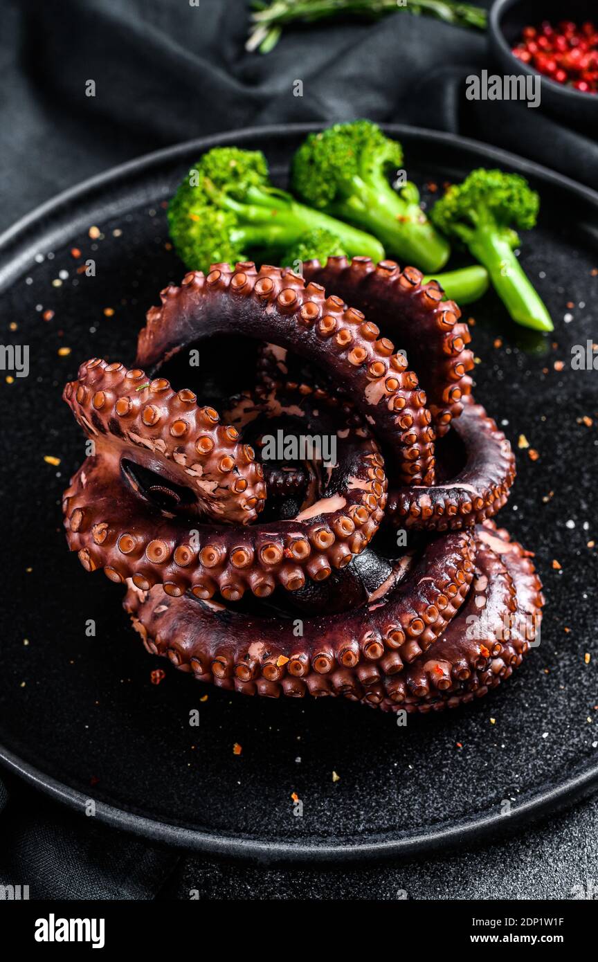 Grilled whole octopus with broccoli on a plate. Black background. Top ...