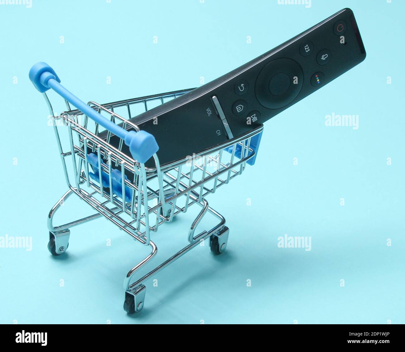 Tv remote in shopping cart for purchases on blue background, consumer ...