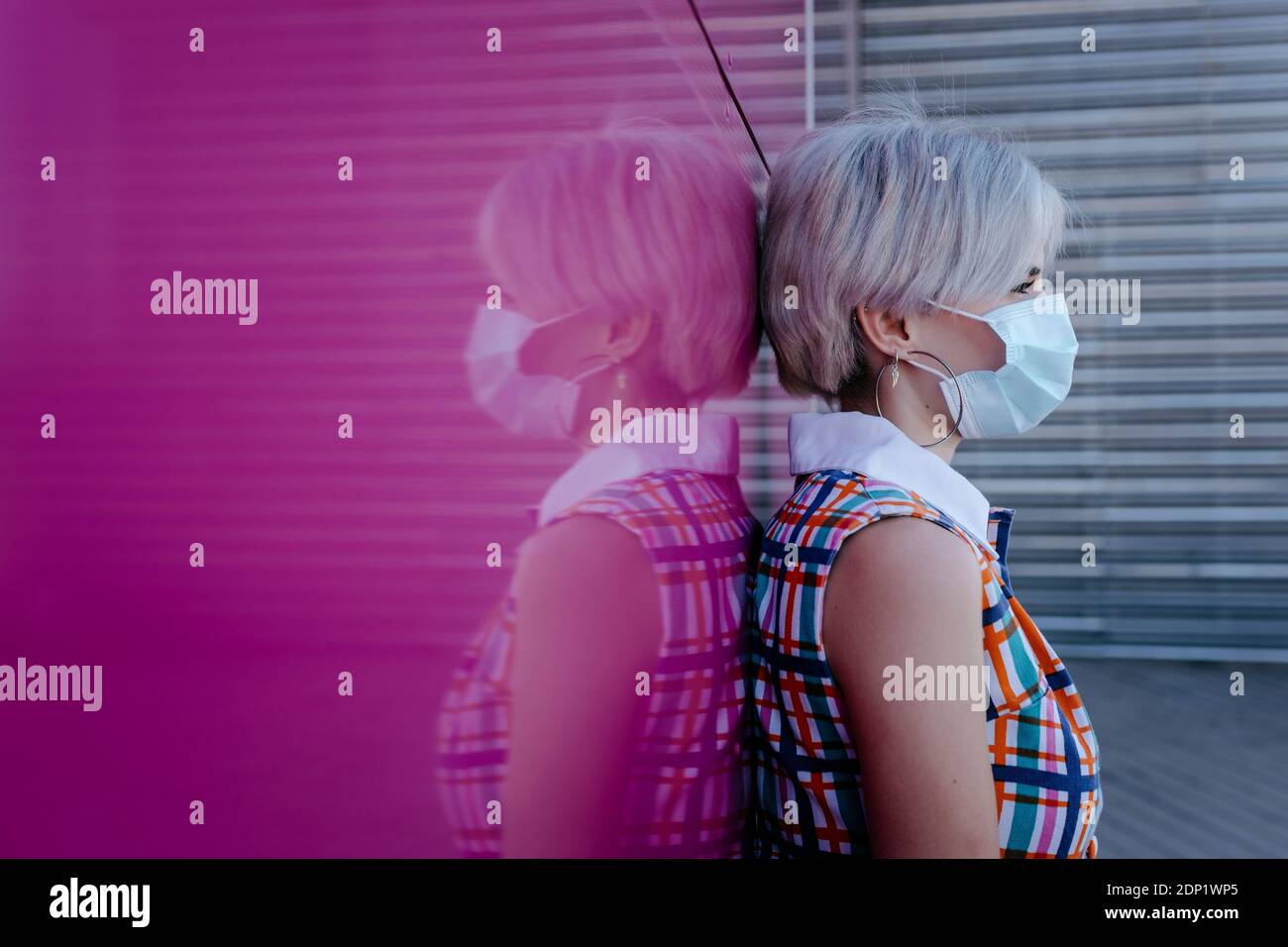 Portrait of girl with face mask, modern urban look and pink glass wall ...