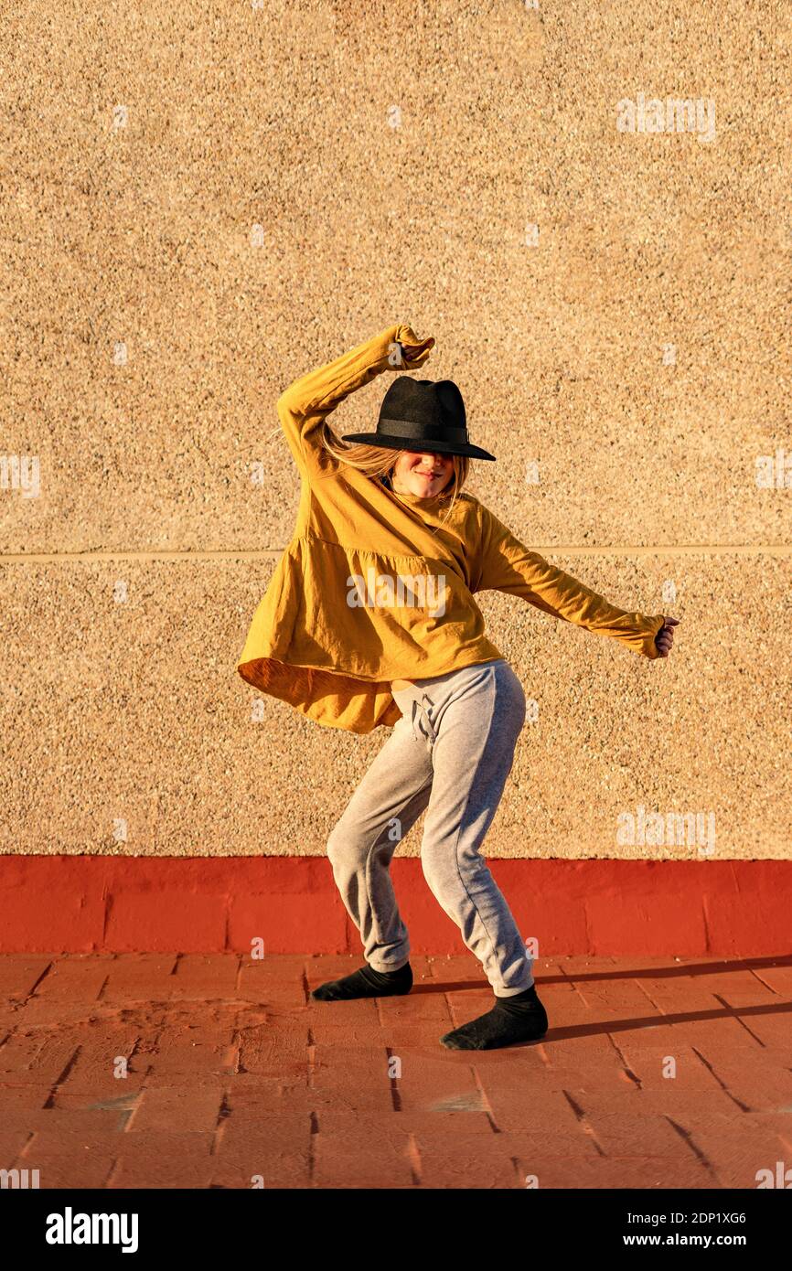 Girl wearing oversized hat dancing on root terrace Stock Photo - Alamy