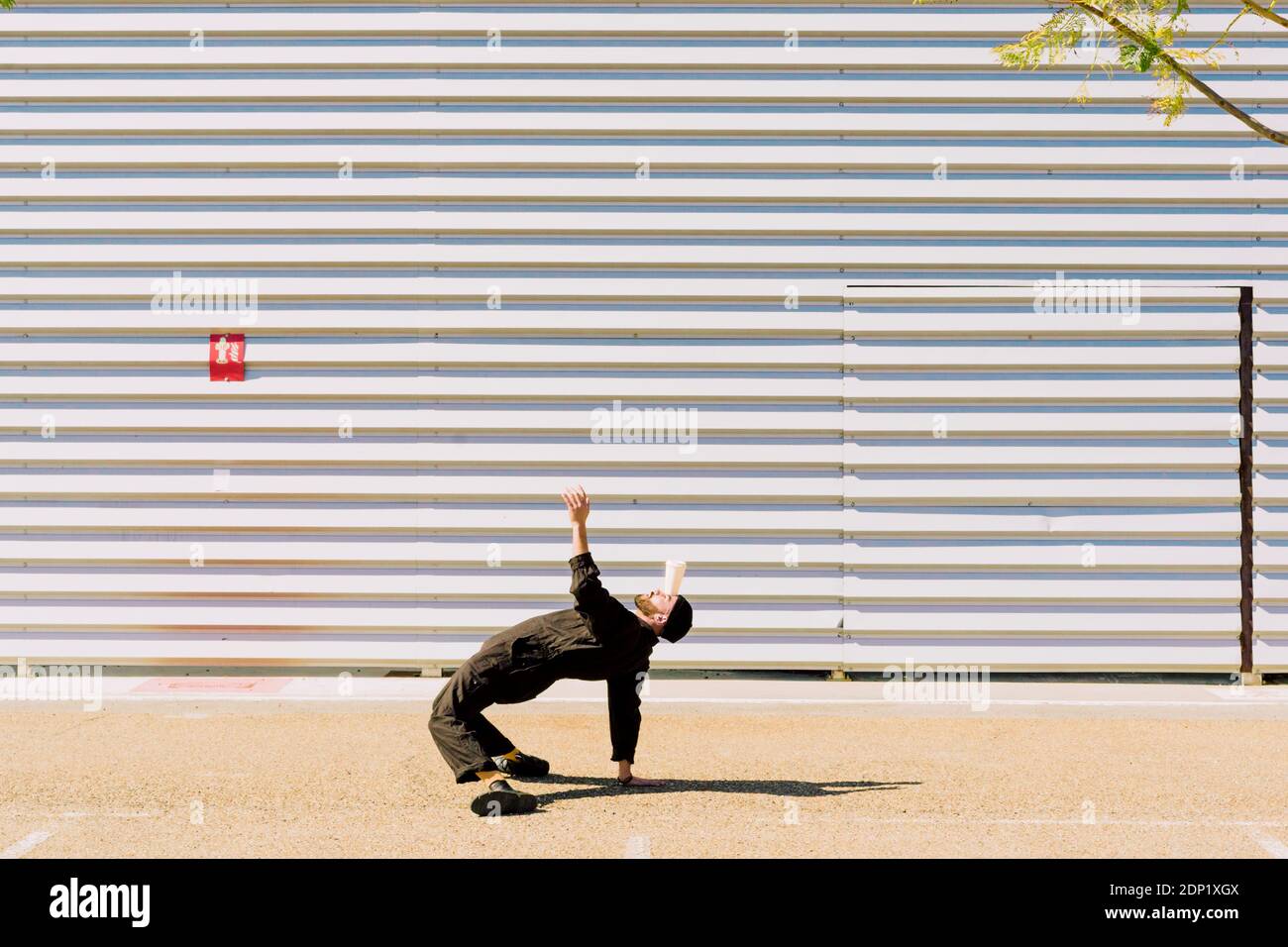 Man wearing black overall balancing cup on his forehead in front of ...