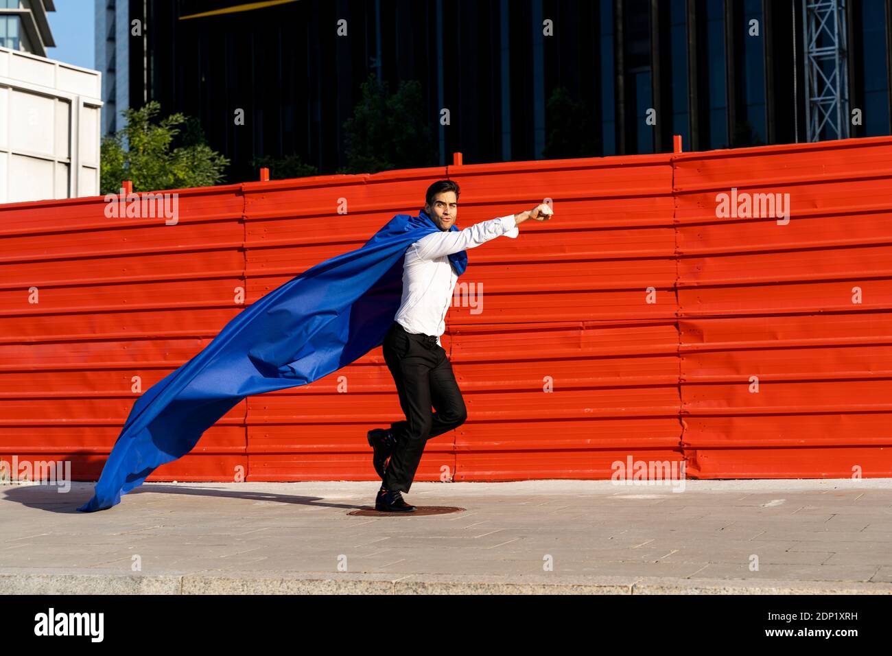 Businessman wearing superhero cape running on pavement Stock Photo - Alamy