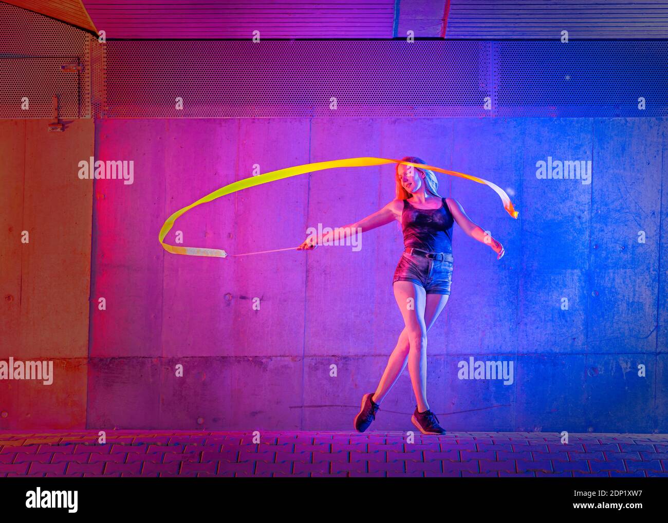 Woman spinning ribbon while dancing against wall Stock Photo - Alamy