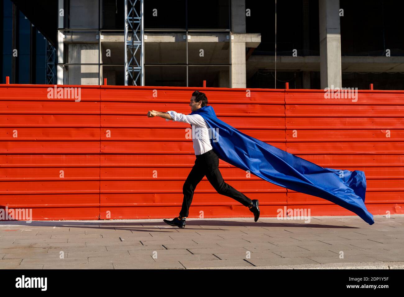 Businessman wearing superhero cape running on pavement Stock Photo - Alamy