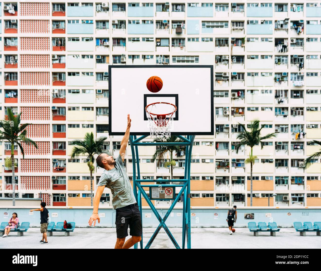 China, Hong Kong, Kowloon, man playing basketball, public housing in ...