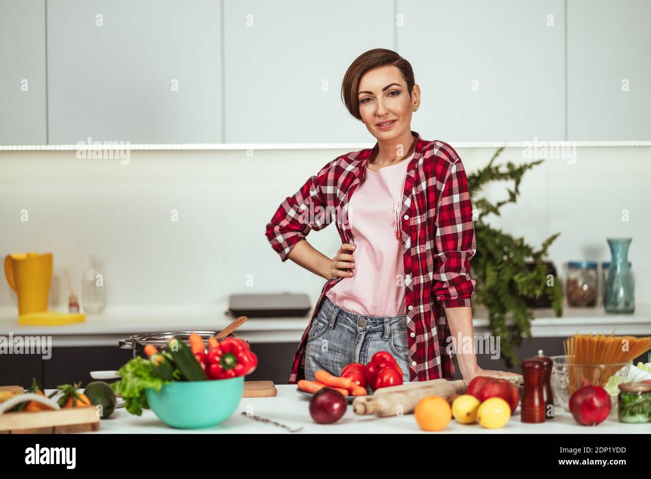Pretty housewife cutting ingredients on table cooking a lunch standing ...