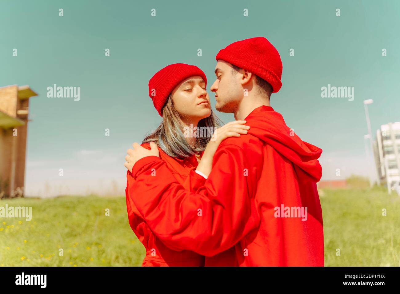 Young couple wearing red overalls and hats standing on a meadow Stock ...