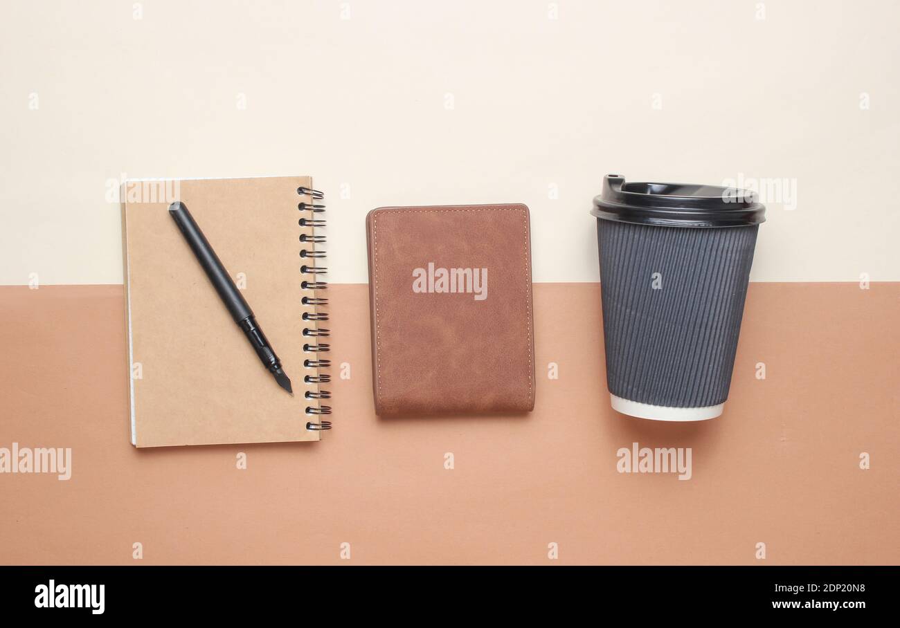 Cup of coffee, notepad with pen, purse on a beige brown paper ...