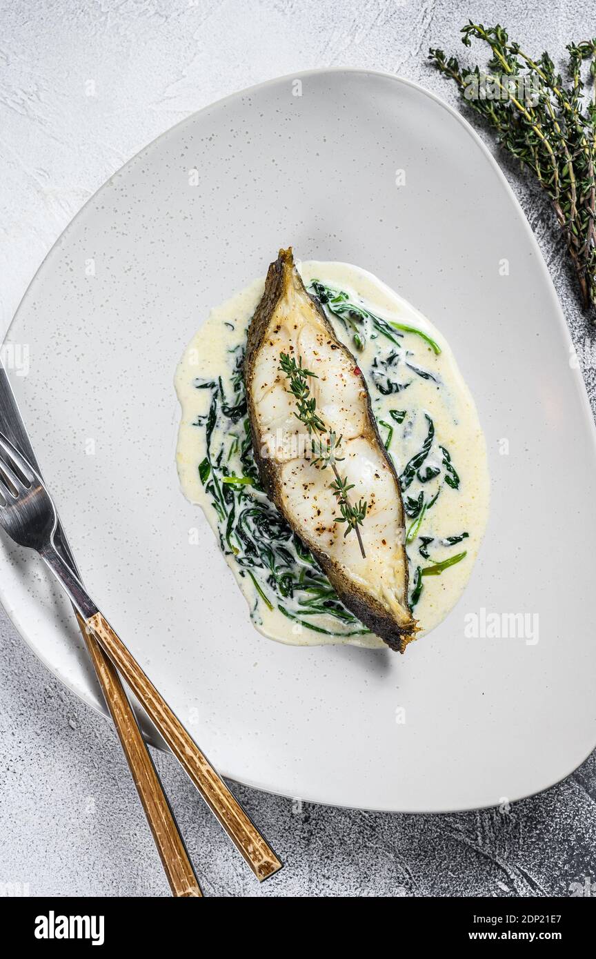 Baked Halibut fish steak with spinach. White background. Top view Stock ...