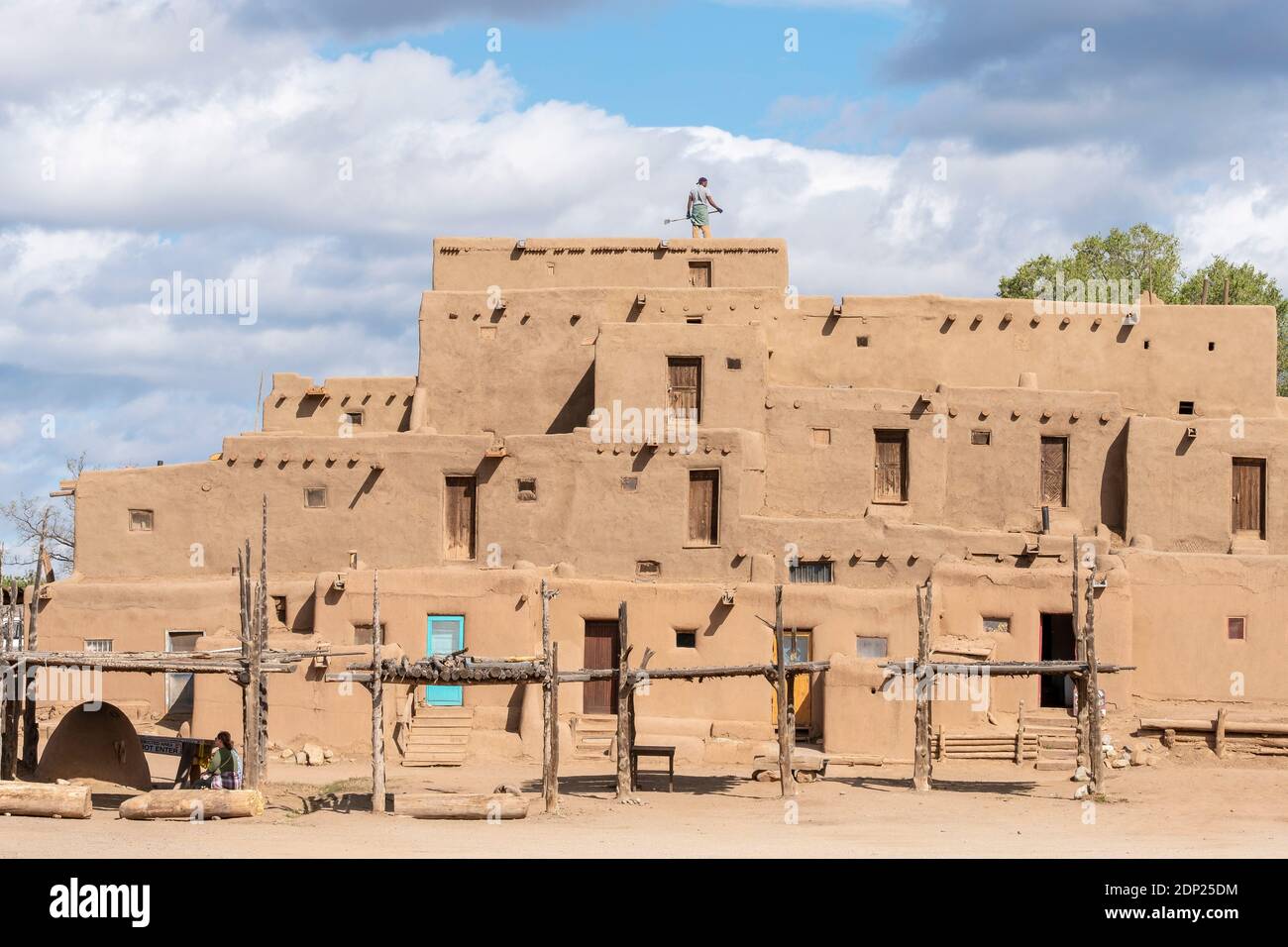 Man cleaning roof of adobe mud brick houses in the historical Native ...
