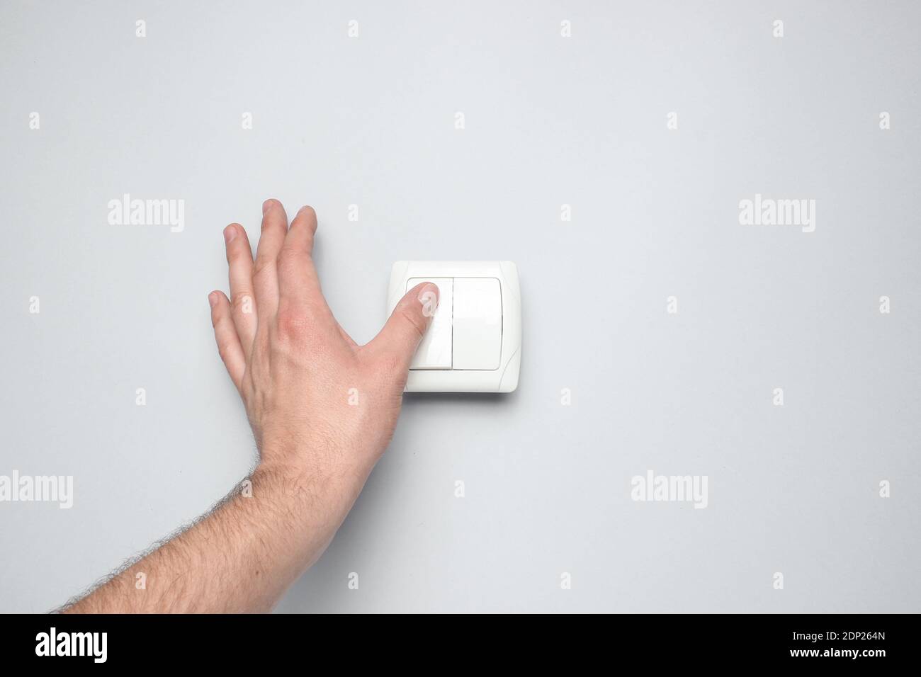 Hand presses a light switch on gray wall background Stock Photo - Alamy