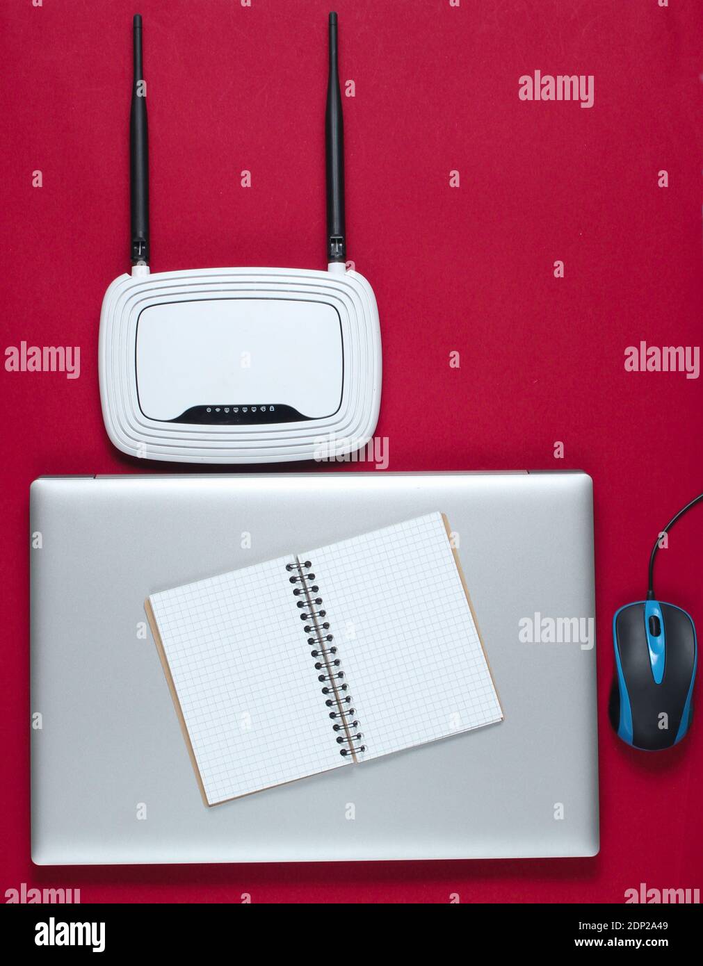 Wi fi router, laptop, pc mouse, notepad on a red background. Top view ...