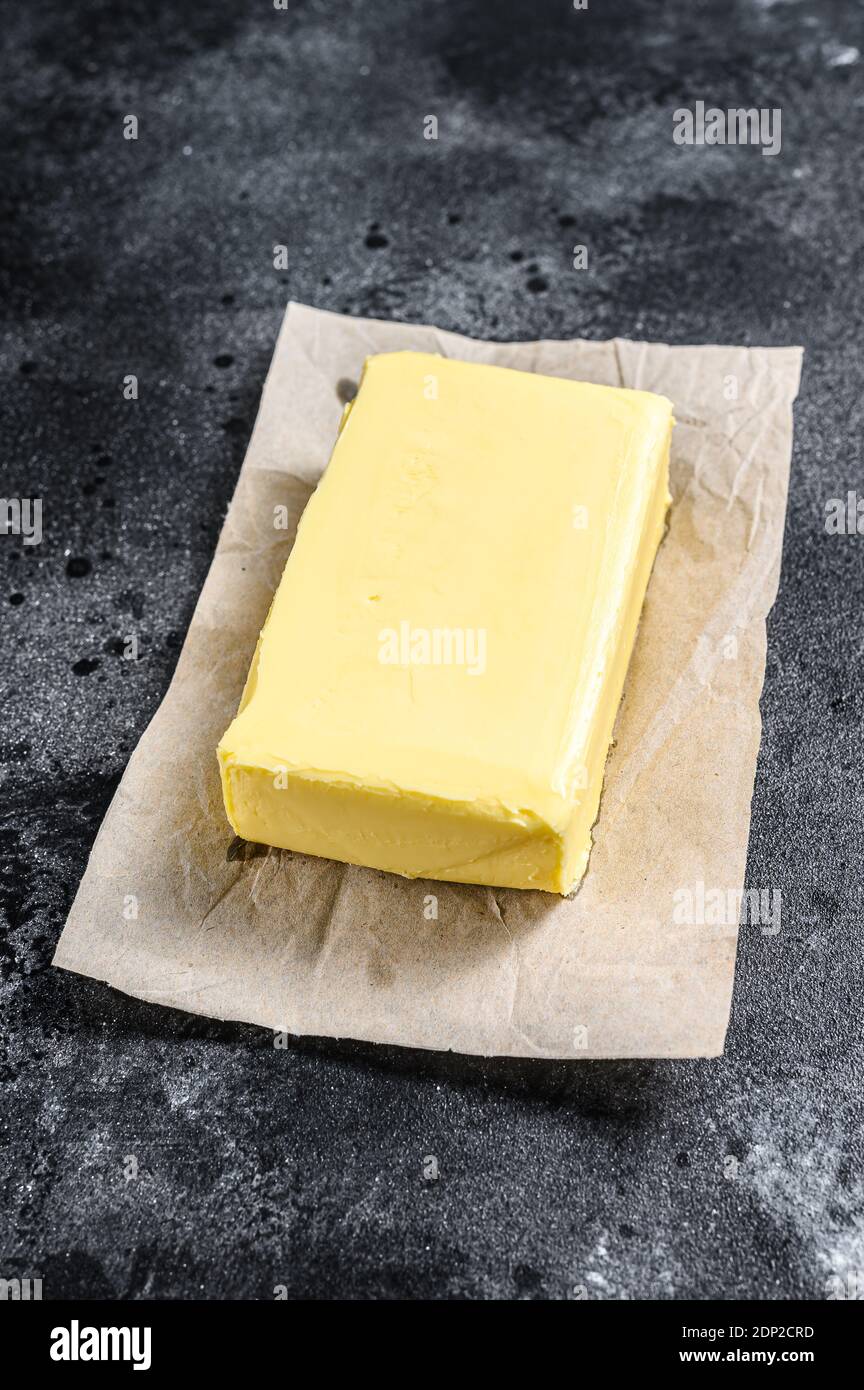 Butter on craft paper, dairy farm products. Black background.Top view ...