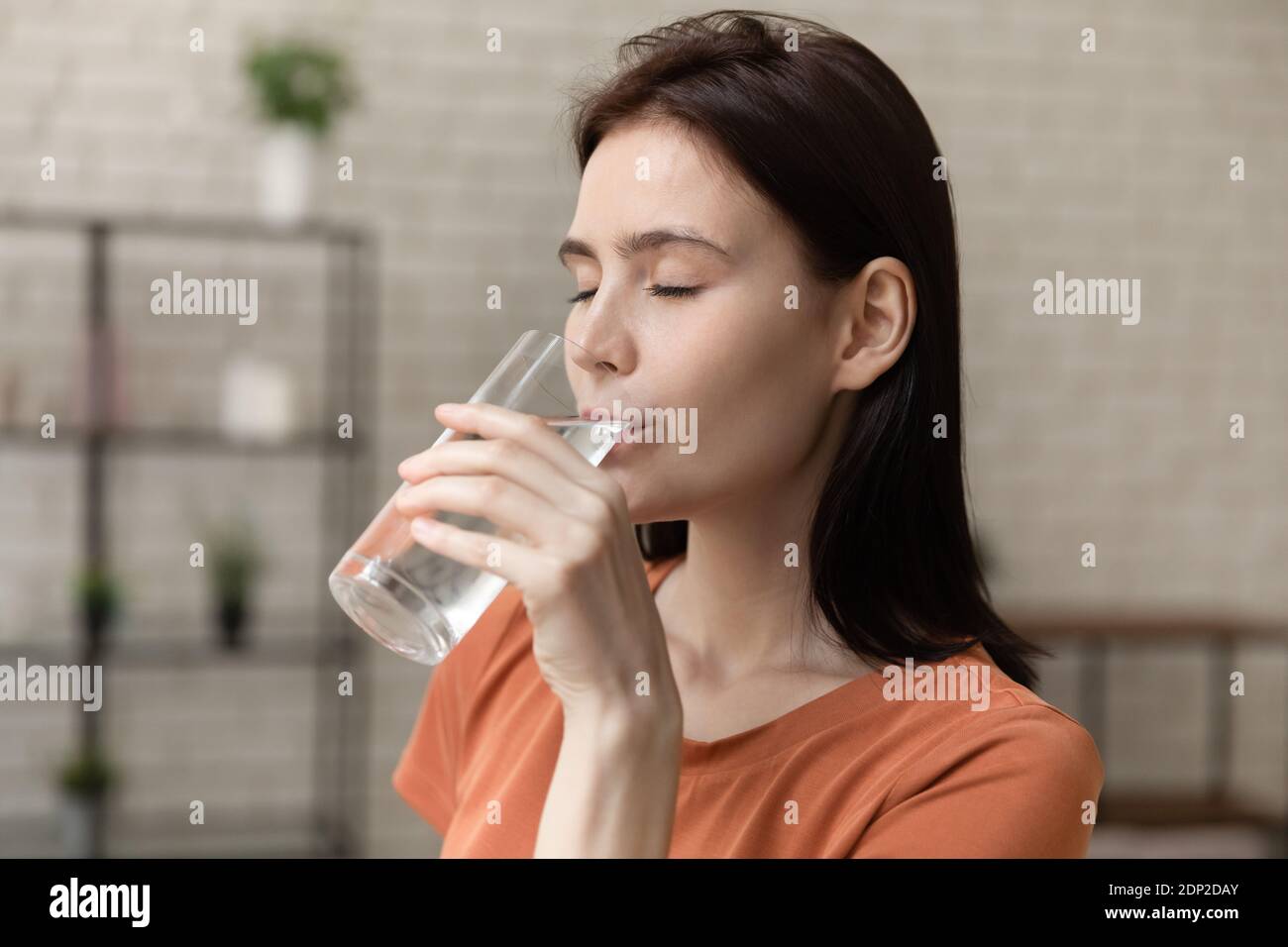 Beautiful millennial female enjoying drinking pure fresh water at home ...