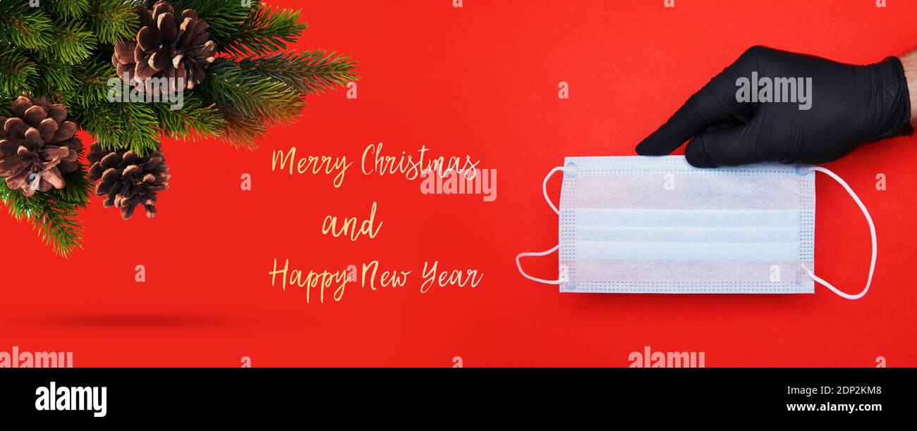 hand in a nitrile glove holds disposable mask and wishes for a merry ...