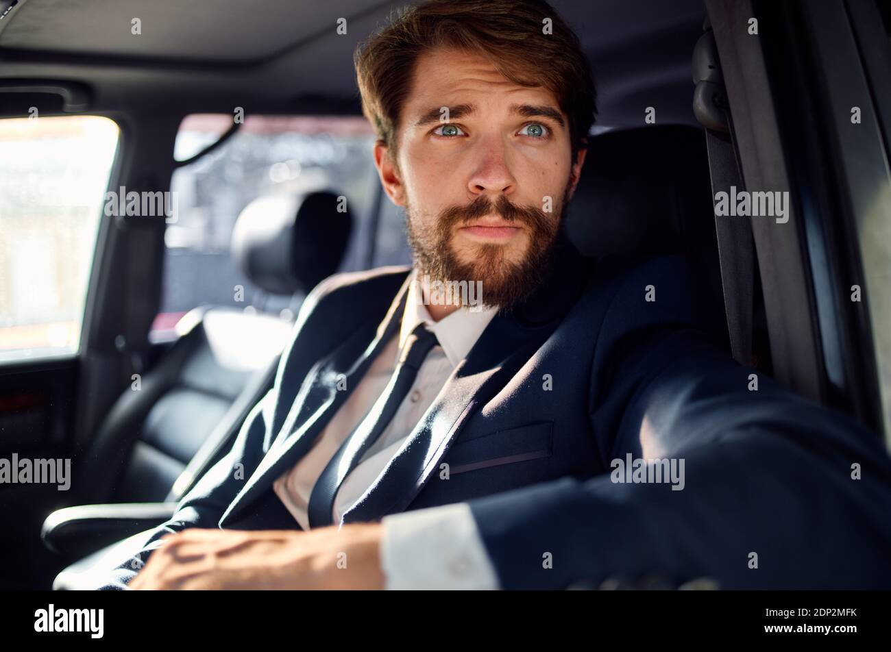 successful rich man in a suit talking on the phone while driving a ...