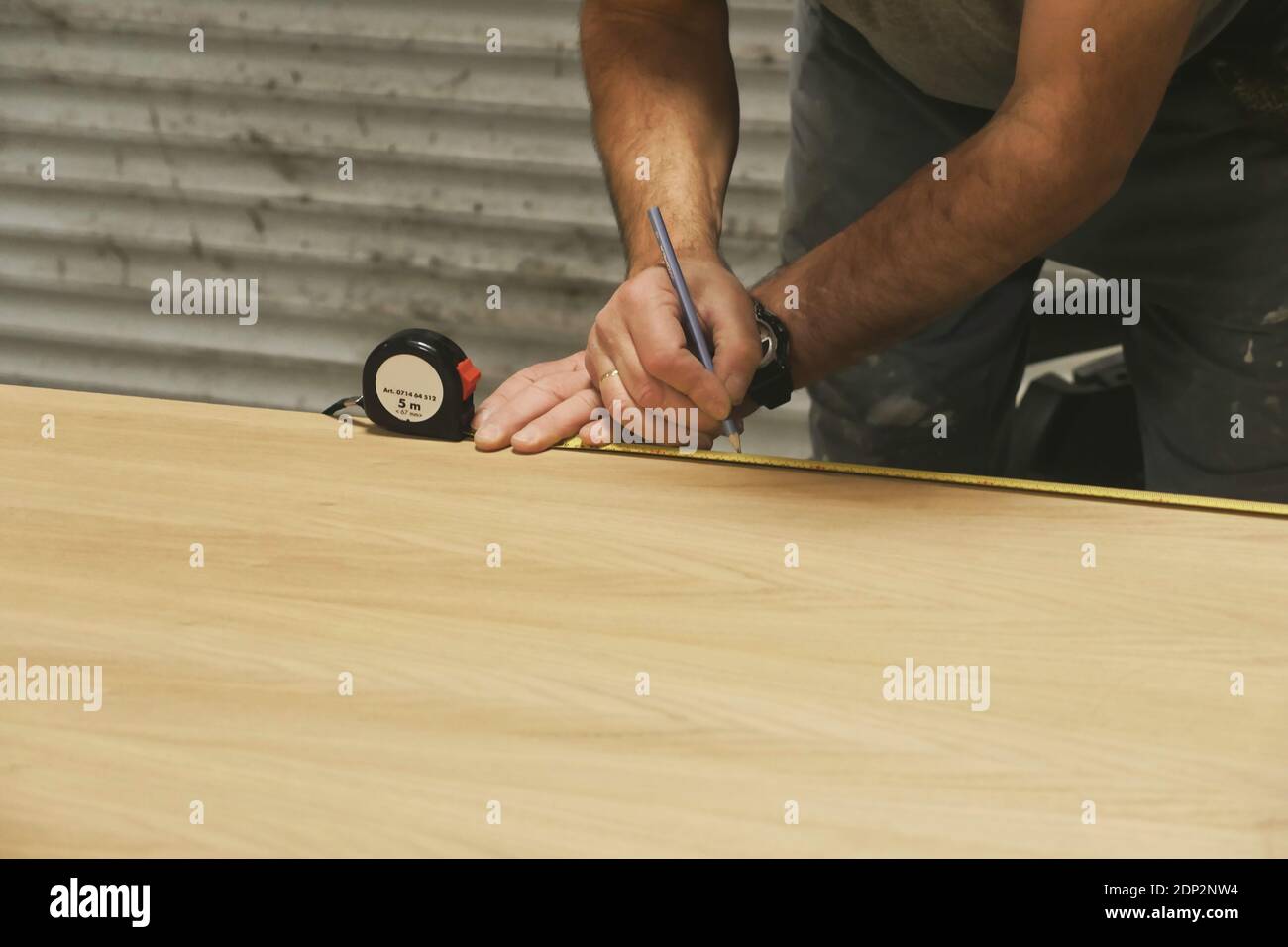 Hand of carpenter lining wooden surface using pencil and tape measure ...