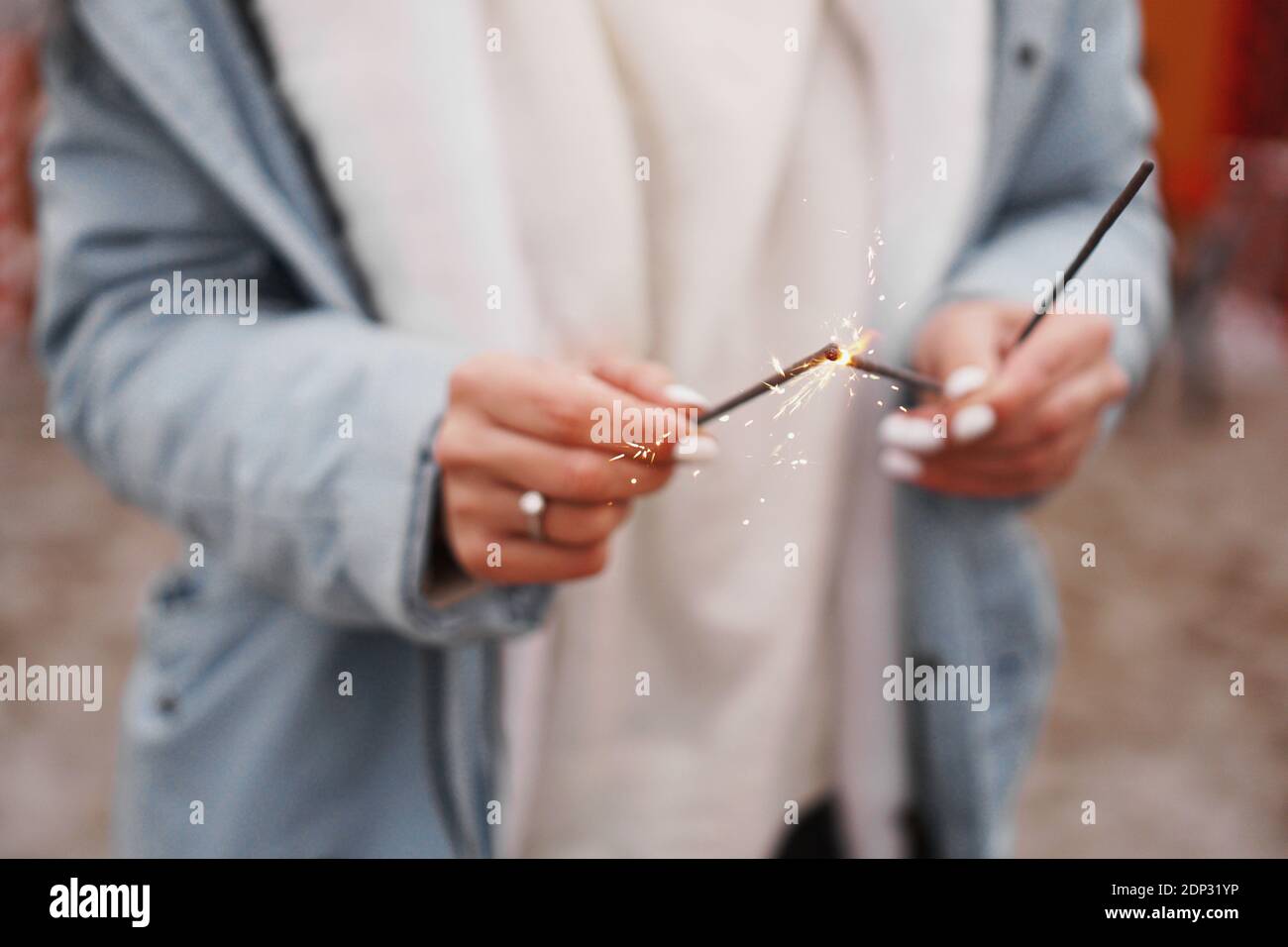 Female hands are holding burning sparklers. Woman outdoors in winter ...